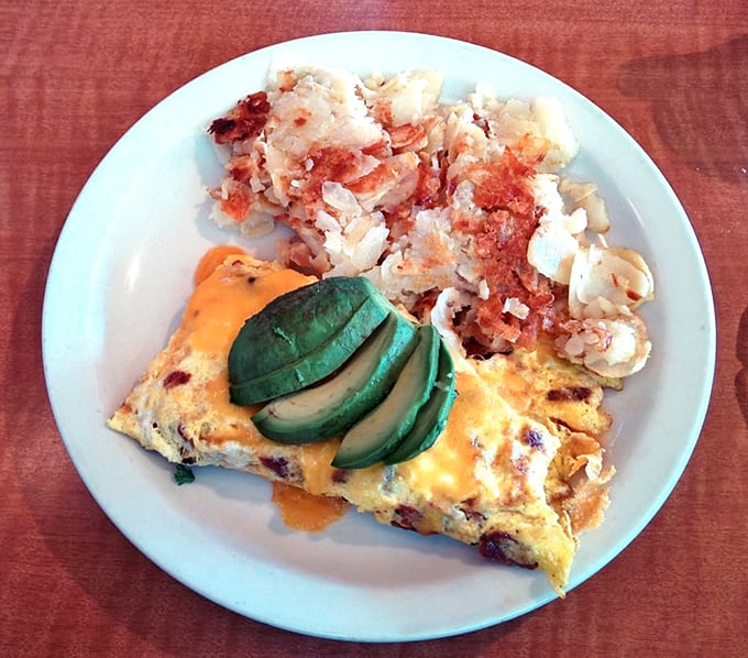 This omelet doesn't just come with avocado—it practically celebrates it, alongside hash browns so perfectly crispy they deserve their own fan club.