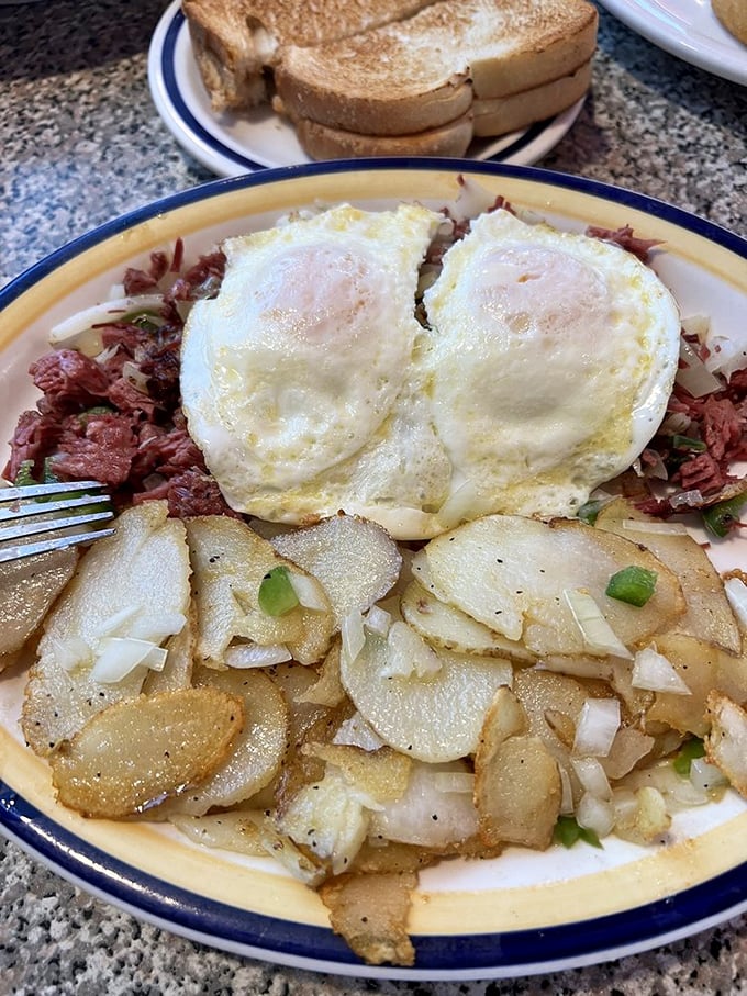Corned beef hash crowned with perfectly cooked sunny-side-up eggs and crispy potatoes – breakfast architecture that would make Frank Lloyd Wright jealous.