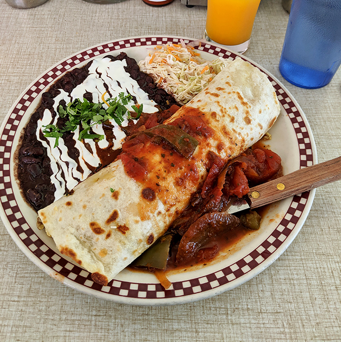 Behold the breakfast burrito in its natural habitat—a tortilla-wrapped masterpiece flanked by black beans and slaw that makes morning meetings worth canceling.