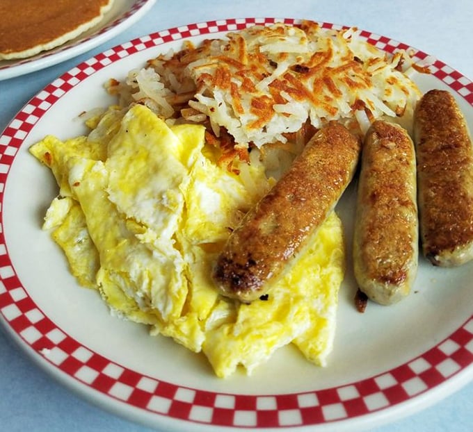 Breakfast perfection on a plate – golden eggs, crispy hash browns, and sausages that would make your cardiologist wince but your soul sing.