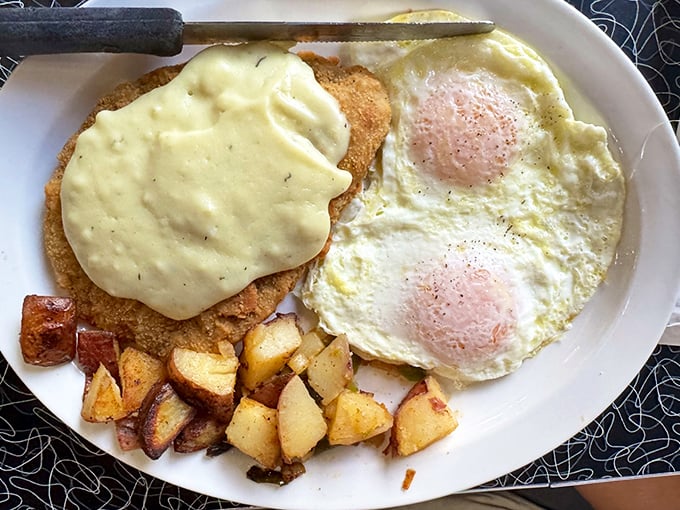 Two sunny-side-up eggs keeping watch over country potatoes and what appears to be chicken fried steak smothered in gravy. Breakfast of champions.