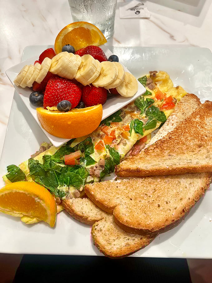 Breakfast artistry at its finest – a perfectly folded omelet alongside a fruit medley so fresh it looks like it's posing for its Instagram debut.