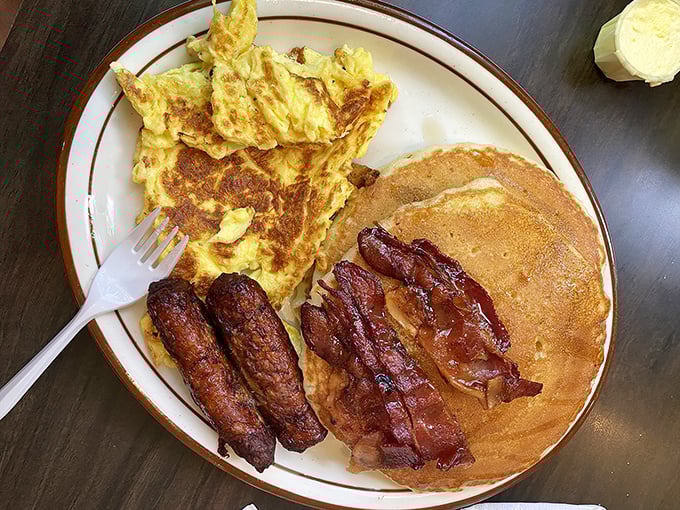 Breakfast perfection on a plate: golden pancakes, crispy bacon, savory sausage, and fluffy eggs—the quartet that's launched a thousand great days.