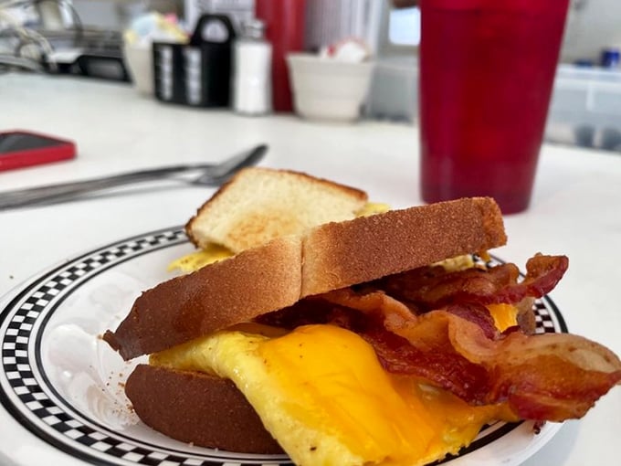 Behold the breakfast sandwich in its natural habitat—where melted cheese meets perfectly cooked eggs and bacon in holy matrimony.