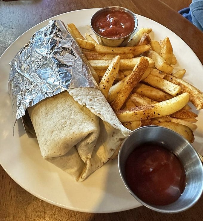 This breakfast burrito doesn't just arrive at your table—it makes an entrance, wrapped in foil like a present, with crispy fries standing guard. Unwrap to unleash happiness.