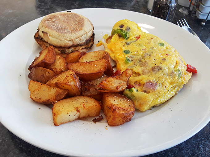 Breakfast nirvana achieved! A perfectly folded omelet alongside golden home fries and an English muffin – the holy trinity of morning satisfaction.