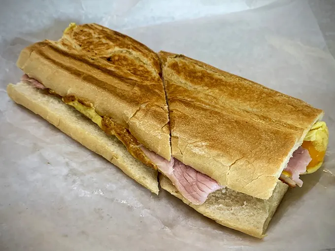 This isn't just breakfast—it's edible architecture where crispy Cuban bread cradles layers of ham and egg in perfect harmony.