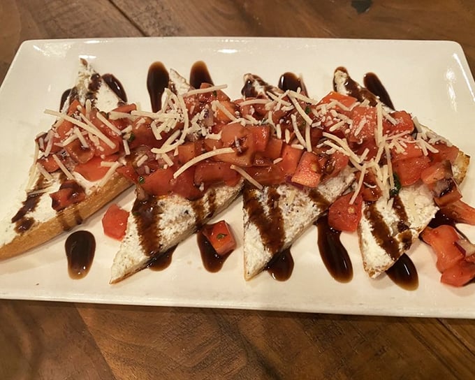 This bruschetta isn't just appetizer – it's edible art. Crisp bread, creamy cheese, fresh tomatoes, and that balsamic drizzle you'd happily drink straight.