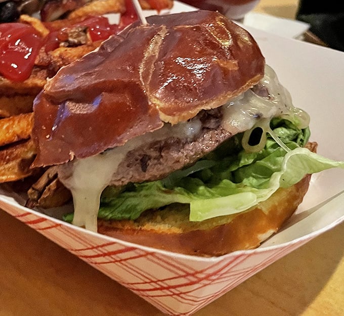 Behold the burger in all its glory—a perfect marriage of juicy patty, melty cheese, and pretzel bun. This isn't just lunch; it's an event worth clearing your calendar for.