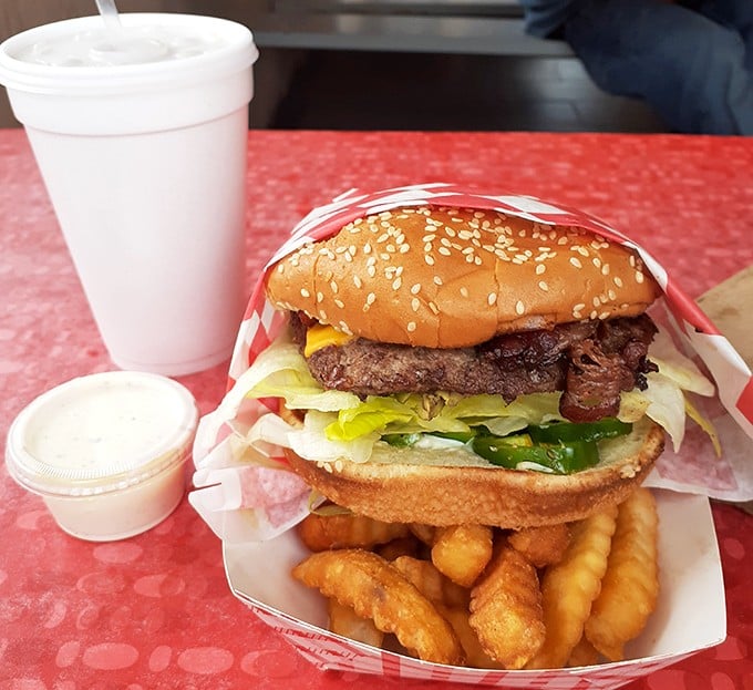 Behold the architecture of satisfaction—a perfectly stacked burger, golden crinkle fries, and a shake that requires serious straw commitment.