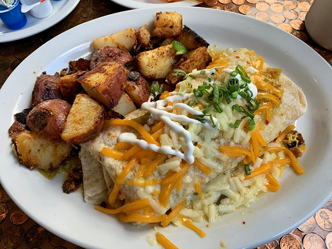 Not just a burrito but an architectural marvel – perfectly wrapped, cheese-crowned, and accompanied by potatoes that deserve their own fan club.