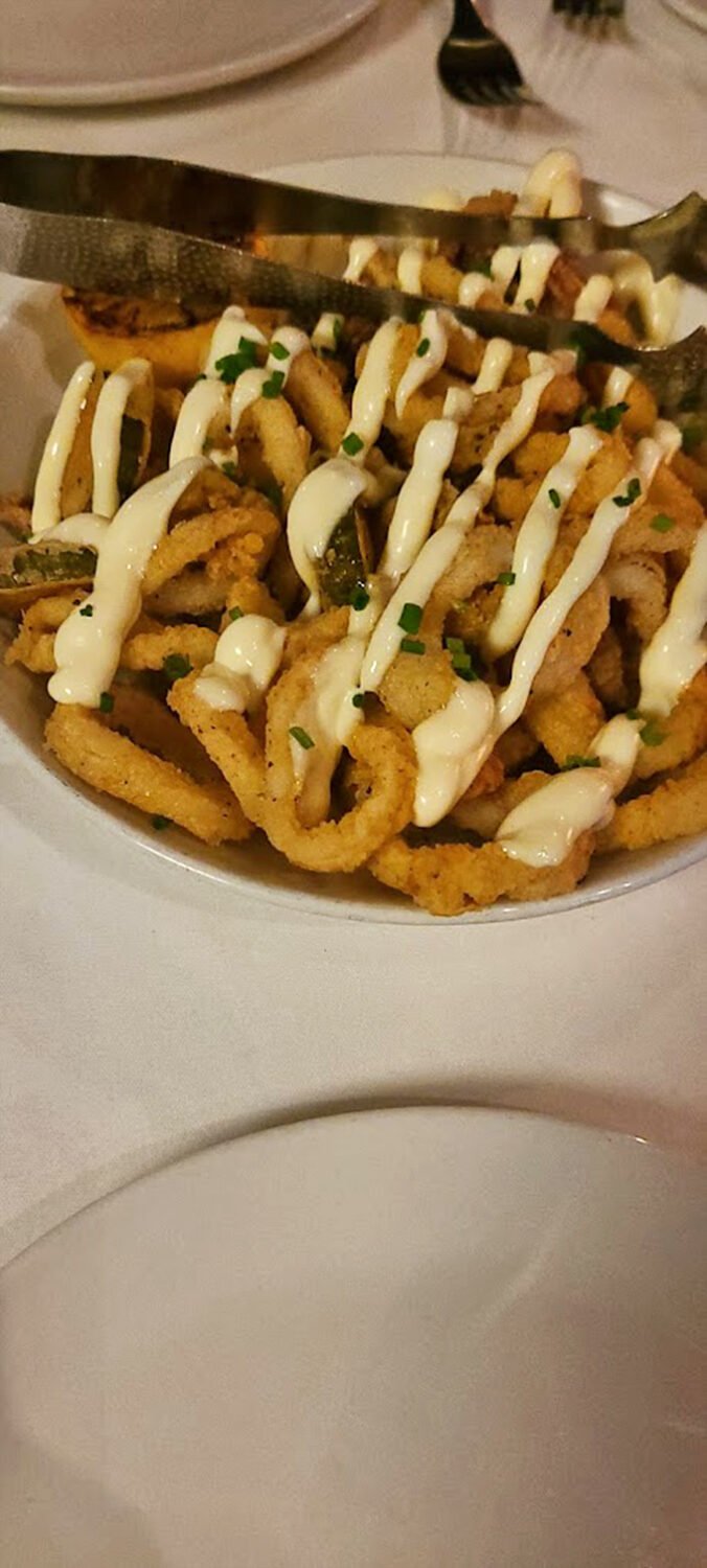 The calamari arrives like the prom king—golden, perfectly dressed, and surrounded by an adoring court of sauce. This isn't bar food; it's a revelation.