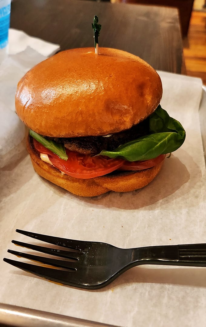 This isn't just a burger – it's architecture. The glossy bun, vibrant tomato, and fresh greens create the kind of stackable perfection that demands a moment of silent appreciation.