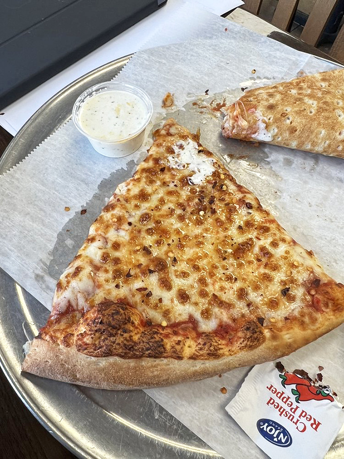 Behold the star of the show—a slice of cheese pizza perfection with that coveted golden-brown speckled top. This is what pizza dreams are made of.