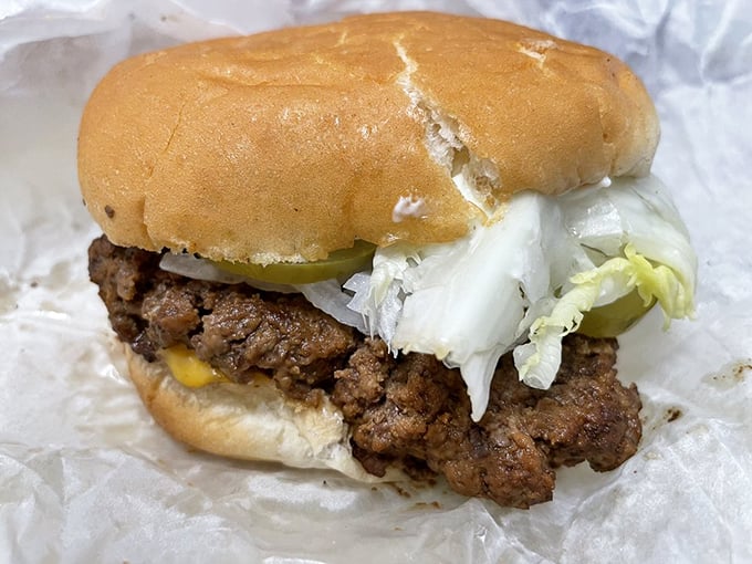 Behold the star of the show—a perfectly pressed patty with melty cheese and fresh toppings. This isn't just a burger; it's edible nostalgia wrapped in wax paper.