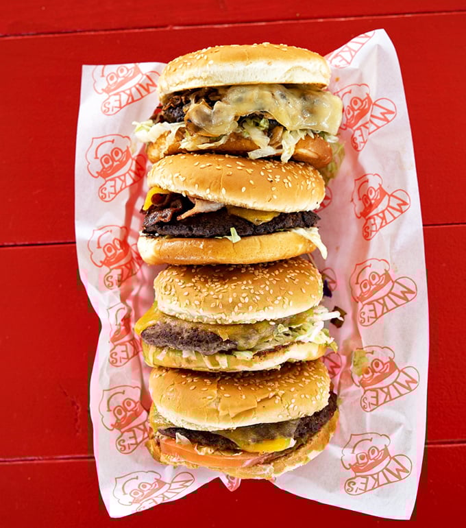 Mike's burgers stack up like a delicious skyscraper of beef, cheese, and veggies—architectural masterpieces you can actually eat.
