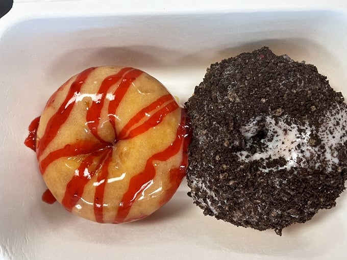 Sweet science in action: a strawberry-drizzled classic alongside what appears to be an Oreo-crusted masterpiece. Two completely different donut personalities sharing one delicious box.