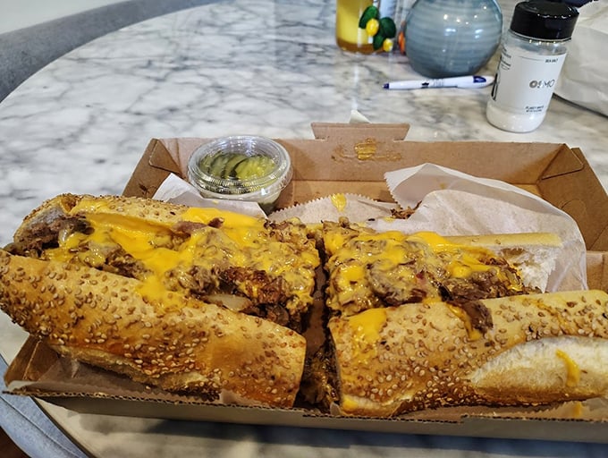 Behold the cheesesteak in its natural habitat – sesame-seeded roll, molten cheese cascading over perfectly chopped steak. Poetry in sandwich form.