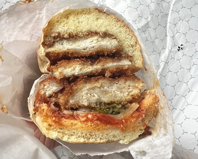 The chicken cutlet sandwich in cross-section reveals its secrets—crispy exterior, juicy interior, and that vibrant sauce creating sandwich perfection.