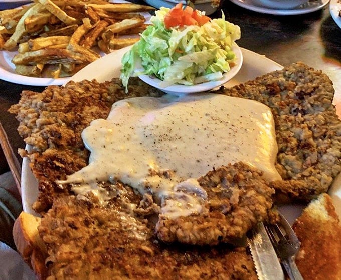 Behold the legendary chicken fried steak in all its glory – a crispy-coated masterpiece drowning in peppery gravy that's worth every mile of the drive.