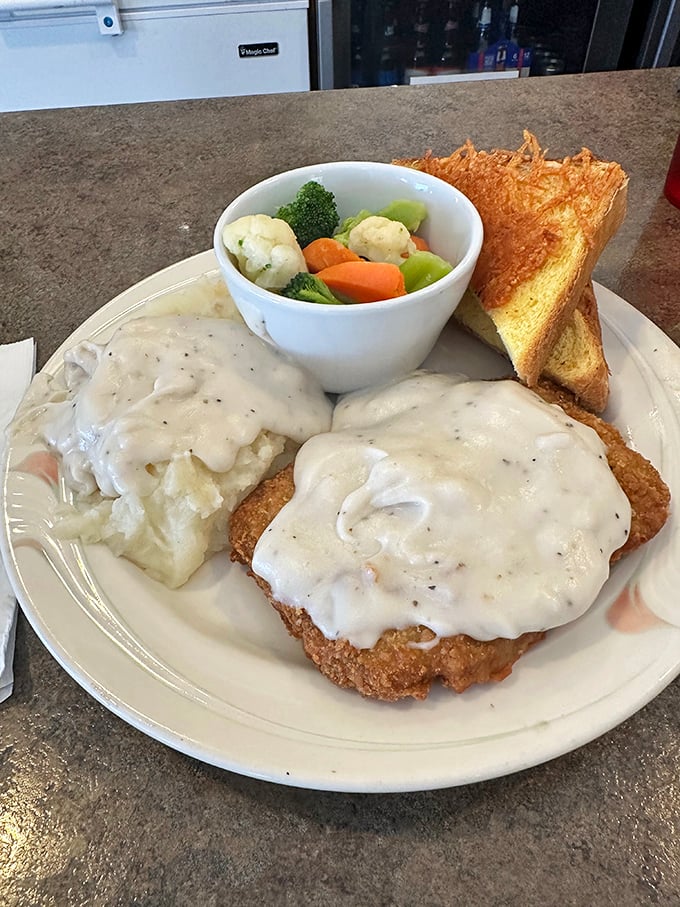 Behold the star attraction: chicken fried steak smothered in country gravy with fresh vegetables and toast. Comfort food that hugs your soul.