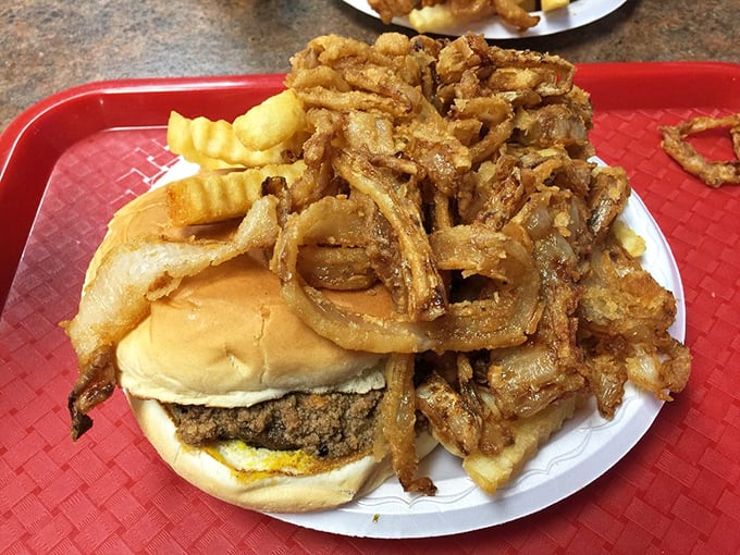 Behold the legendary "A-Plenty" in its natural habitat—a burger avalanched under a mountain of crispy onion rings and fries.