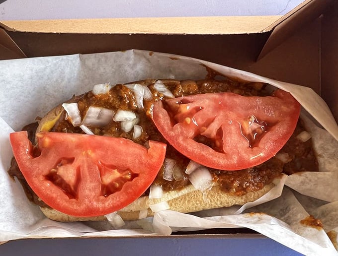 Chili dog perfection in its natural habitat. Those tomato slices aren't just garnish—they're the cool, fresh counterpoint to that rich, meaty chili blanket.