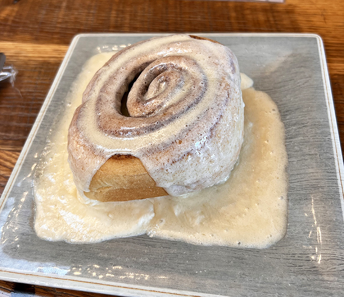 Behold the star attraction: a cinnamon roll so magnificent it deserves its own zip code. That pool of frosting isn't just decoration—it's liquid happiness.