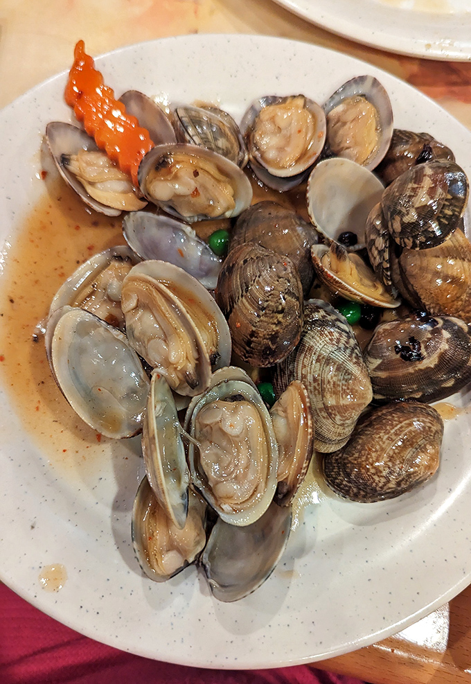 These clams aren't just cooked, they're transformed—plump, tender morsels bathed in a savory broth that demands to be sopped up with anything available.