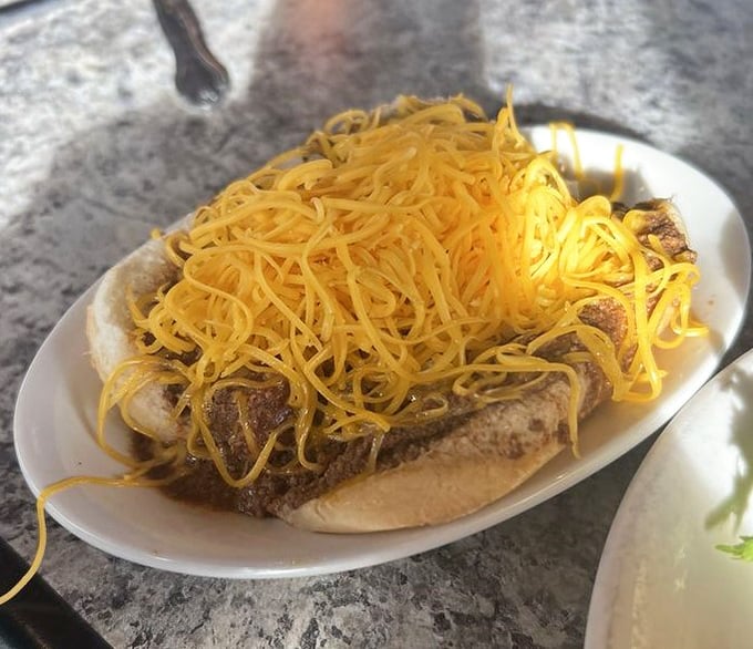 Behold the Cincinnati coney in all its glory—a hot dog practically wearing a yellow cheese toupee that would make any food lover weak at the knees.