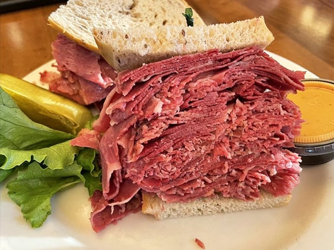 Behold the masterpiece: layers of hand-sliced corned beef stacked higher than your expectations, with a pickle standing guard nearby.