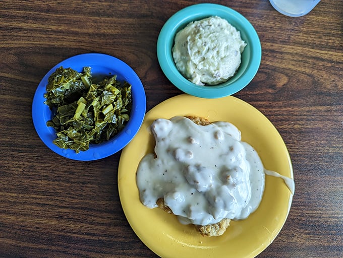 Southern cooking 101: A perfect biscuit drowning in creamy sausage gravy alongside collard greens and mashed potatoes. Cardiologists hate this photo.