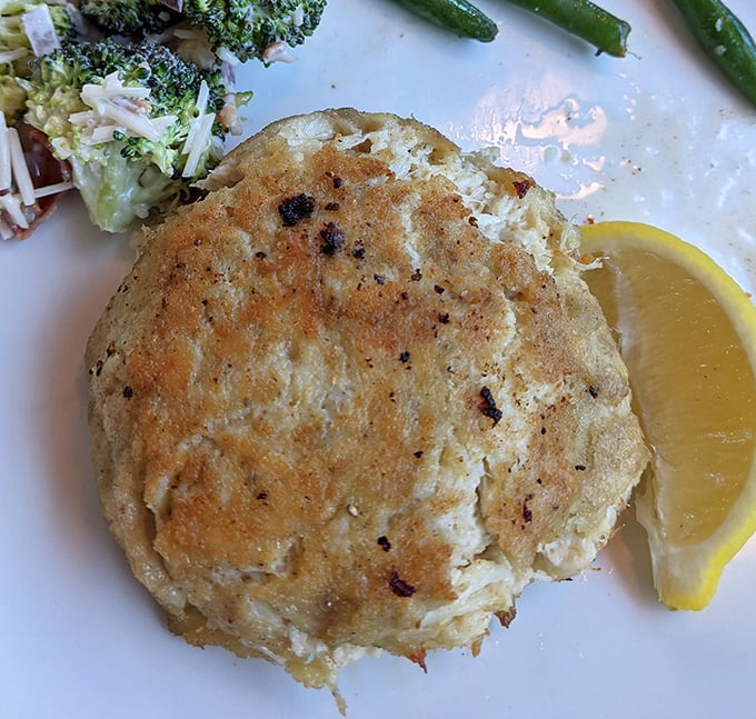 Behold the star of the show—a golden-brown crab cake that's more crab than cake, sitting proudly like Delaware's answer to the Hope Diamond.