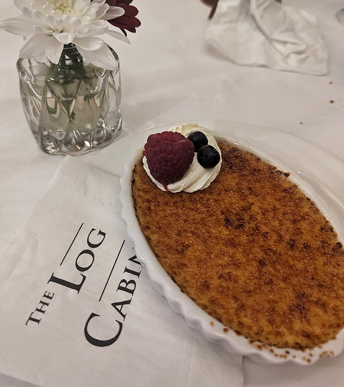 Behold the legendary crème brûlée—its perfectly caramelized top waiting to be cracked like nature's most delicious geode, crowned with fresh berries.