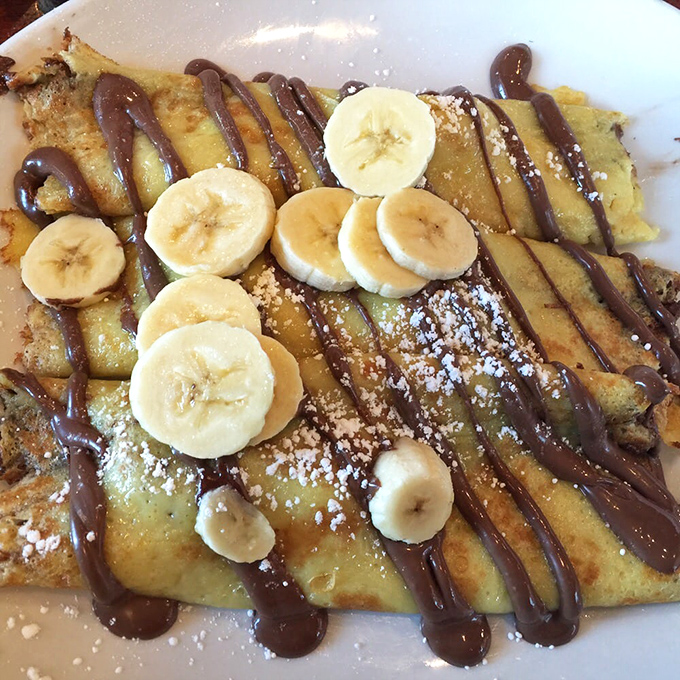 Chocolate drizzles dance across golden crepes while banana slices stand at attention. This isn't breakfast – it's edible architecture with a side of joy. 