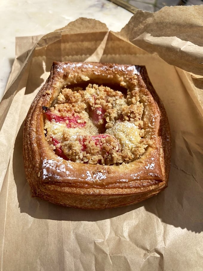 This fruit danish isn't just breakfast—it's edible architecture with its perfectly laminated layers and ruby-red filling peeking through a golden crumble top.