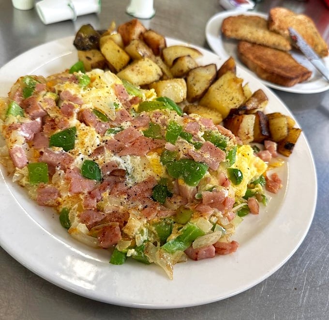 The Denver Omelet in all its glory – perfectly fluffy eggs cradling ham, peppers, and cheese with crispy potatoes standing guard on the side.