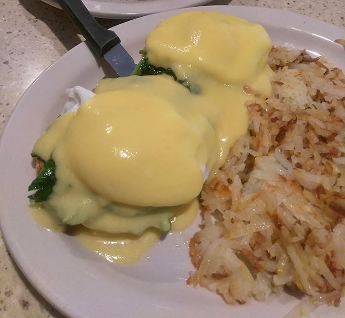Behold the star attraction: eggs Benedict with perfectly poached eggs draped in hollandaise that cascades like a golden waterfall, accompanied by crispy home fries.