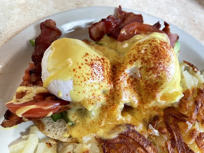 Behold the holy grail of breakfast—eggs benedict with perfectly poached eggs where the yolks cascade like liquid sunshine over crispy bacon and English muffins.