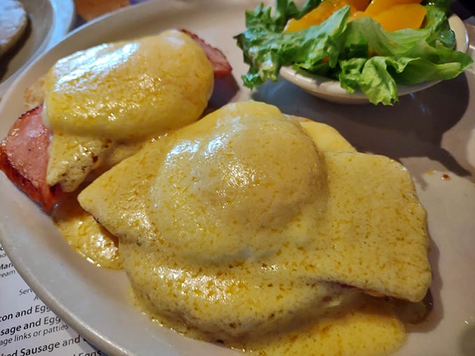 Behold the Eggs Benedict in all its golden glory – two perfectly poached eggs doing a synchronized swimming routine in a pool of buttery hollandaise.