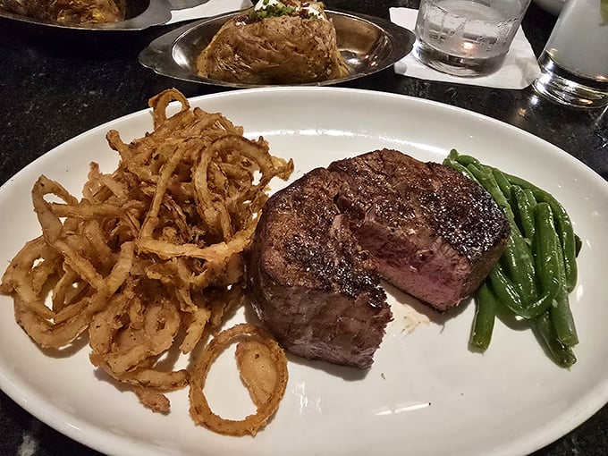 Behold the star of the show—a perfectly seared filet mignon flanked by crispy onion strings and vibrant green beans. Meat poetry on a plate.