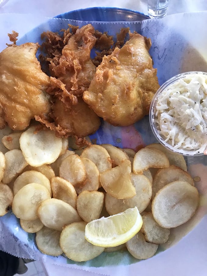 This isn't just fish and chips; it's edible architecture—golden-battered cod perched atop a foundation of crispy potato medallions with coleslaw for balance.