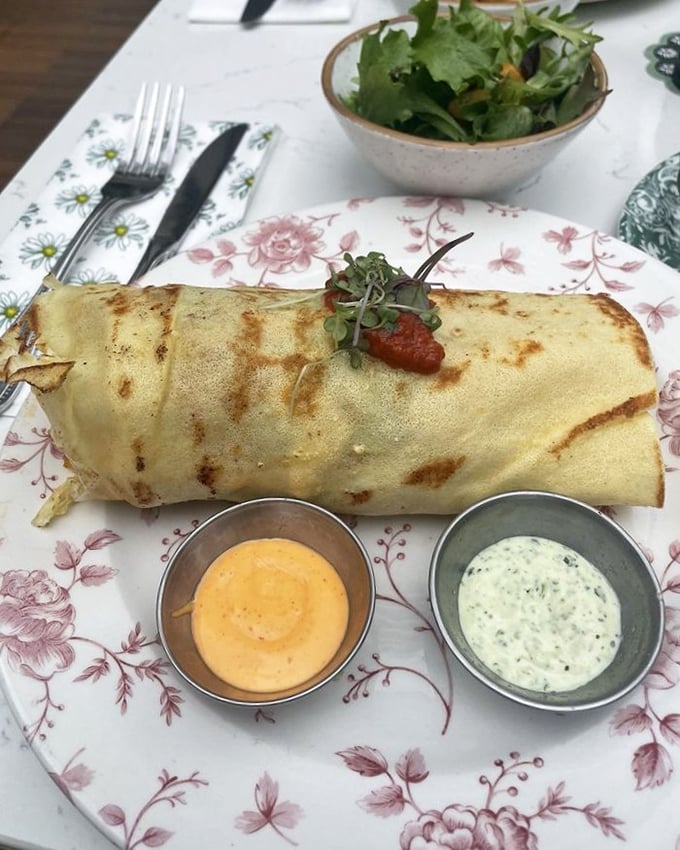 The French Breakfast Burrito arrives like a diplomat between two culinary worlds, with perfectly golden tortilla and two diplomatic sauces negotiating for your taste buds.