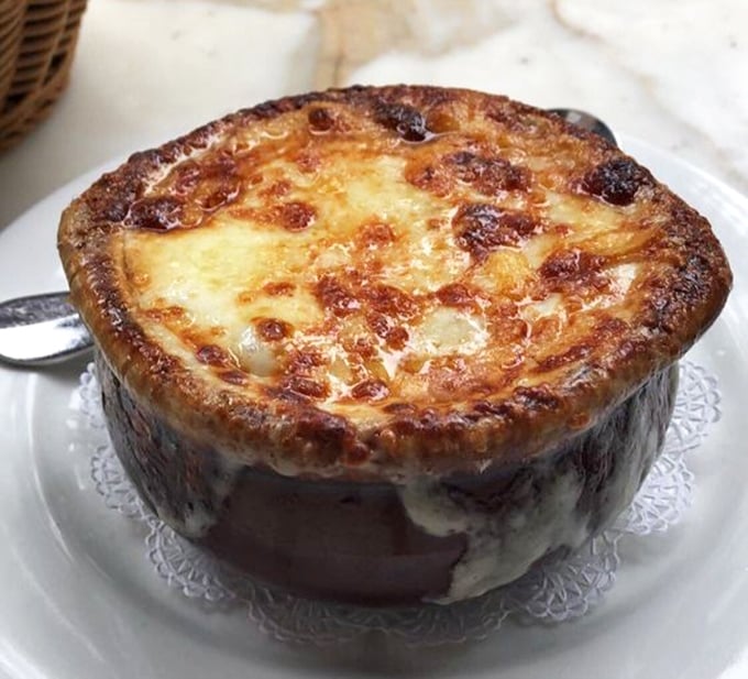This isn't just French onion soup—it's a volcanic masterpiece of bubbling cheese concealing a rich, beefy broth that would make Julia Child weep with joy.