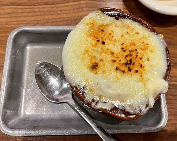 This isn't just French onion soup—it's a religious experience in a crock, with a cheese canopy that stretches skyward like the dreams of hungry diners.