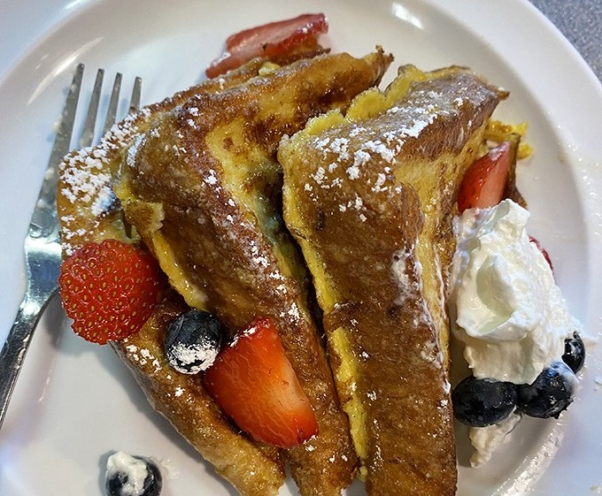 French toast that deserves its own Instagram account—crispy edges, custardy centers, and fresh berries that pop like edible jewels.