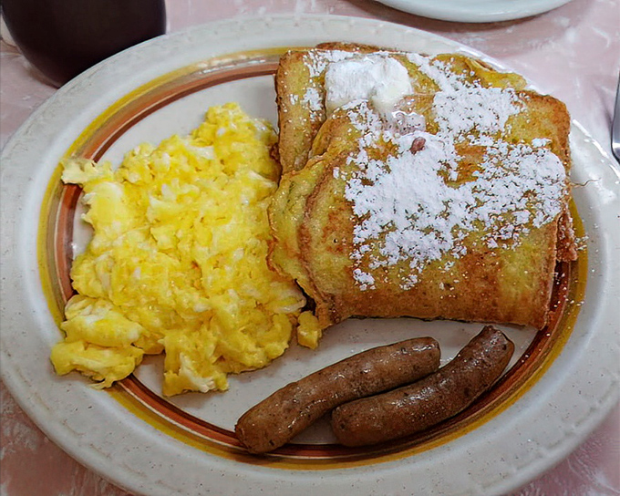 The French Toast Combo in all its glory – golden-brown perfection dusted with powdered sugar, alongside eggs and sausage that make waking up worthwhile.