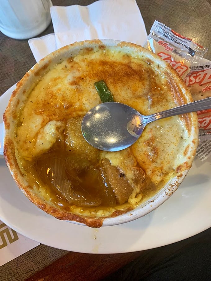 The legendary French onion soup arrives with a cheese canopy that stretches like the finale of a culinary magic show.