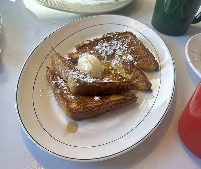 This French toast doesn't need fancy toppings or Instagram filters – just thick-cut bread transformed into golden perfection with a dusting of powdered sugar and a dollop of butter.