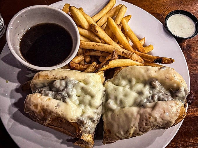 The French Dip arrives like a work of art – melted cheese cascading over tender beef, with that magical au jus waiting to transform each bite.